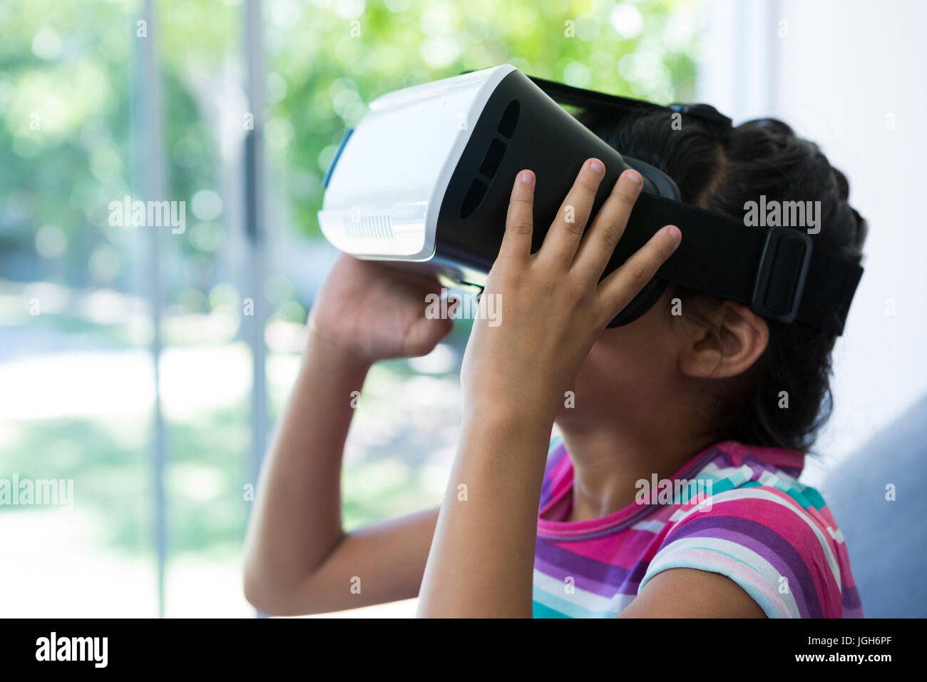 Side view of girl wearing virtual reality simulator while sitting on ...