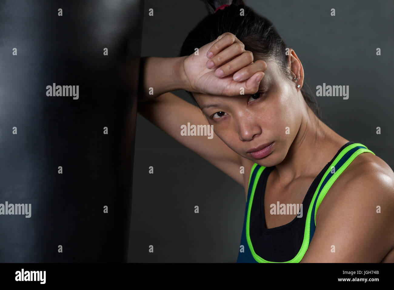 Portrait of sad man leaning on punching bag in fitness studio Stock ...