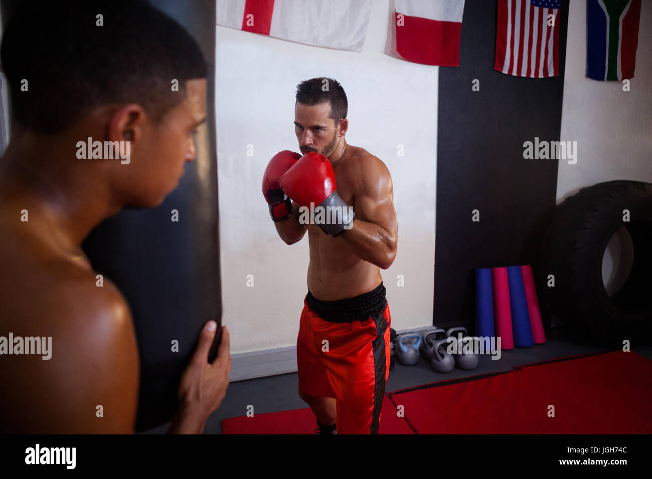 Trainer assisting man in boxing at fitness studio Stock Photo - Alamy