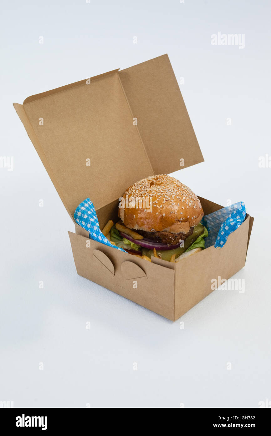 Hamburger in a take away container on table against white background ...