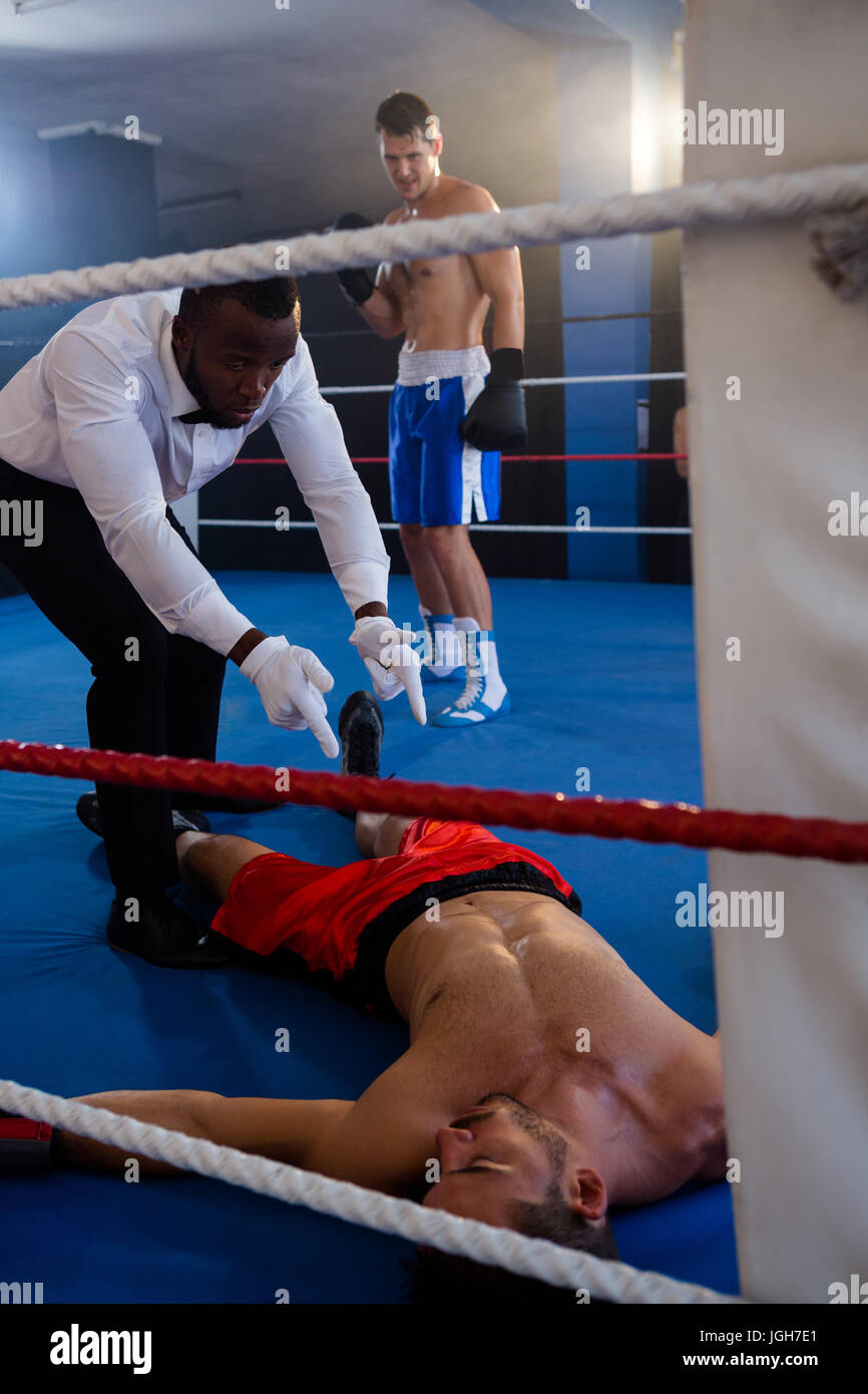 Referee counting by unconscious male boxer in boxing ring Stock Photo ...