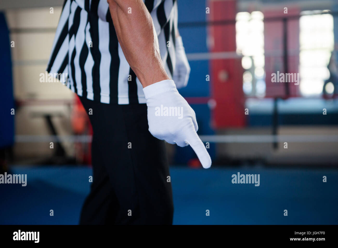 Midsection of male referee pointing down while standing in boxing ring ...