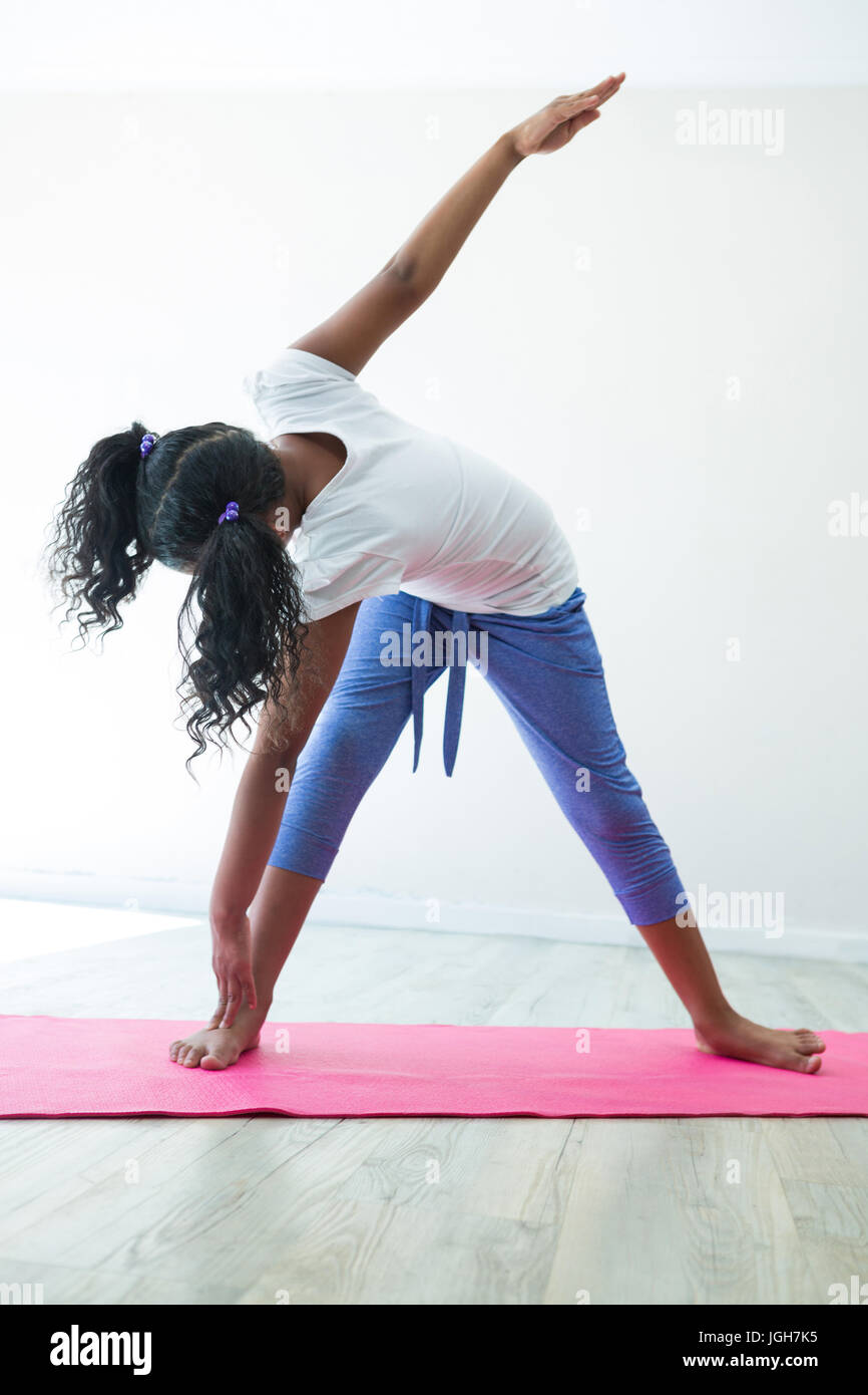 Girl bending while exercising against wall in room Stock Photo - Alamy