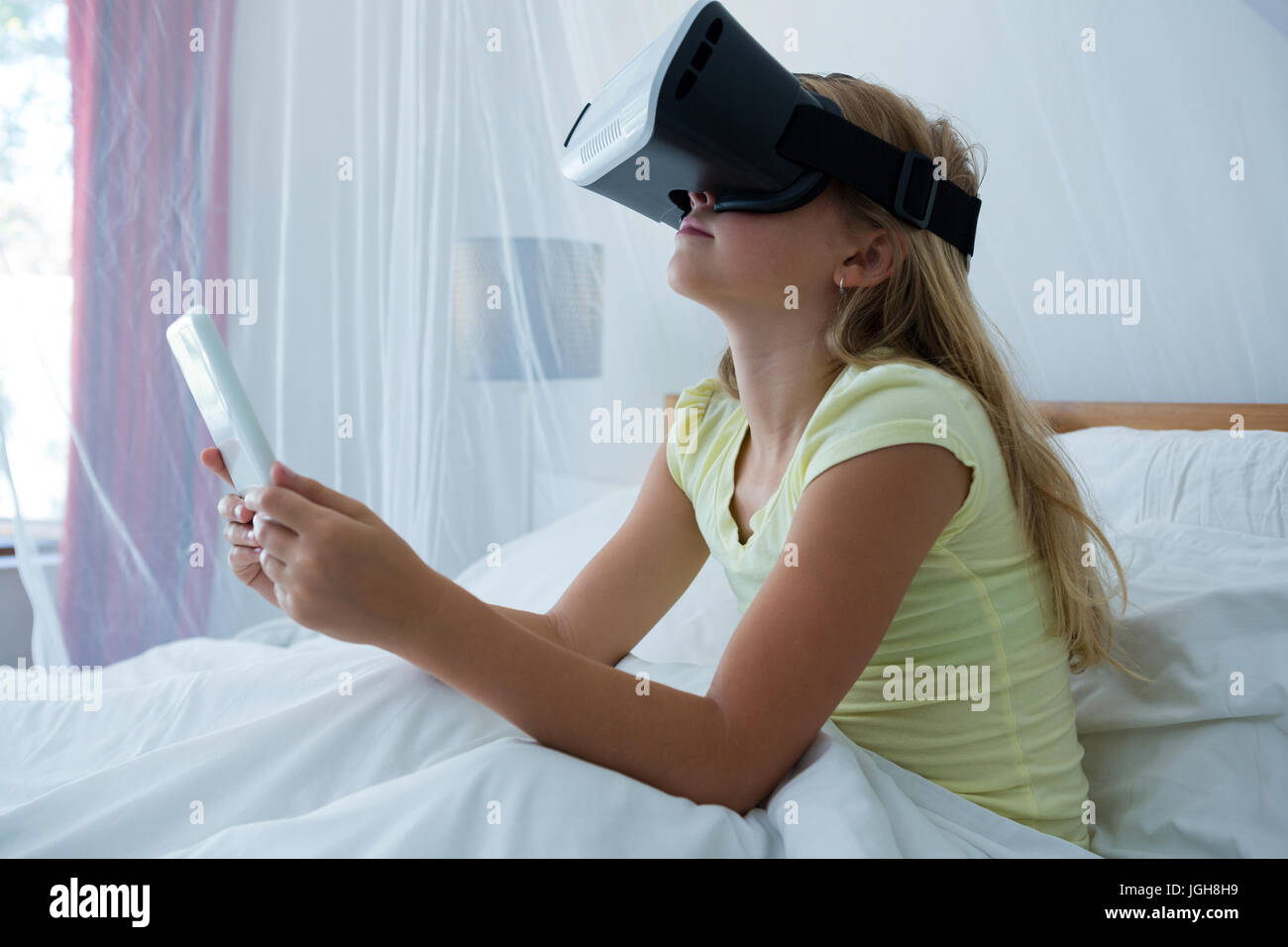 Side view of girl holding tablet while wearing virtual reality ...