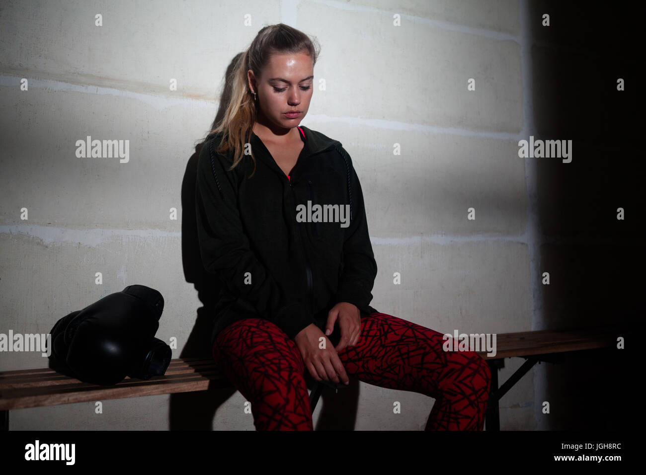 Sad woman relaxing on bench in fitness studio Stock Photo - Alamy
