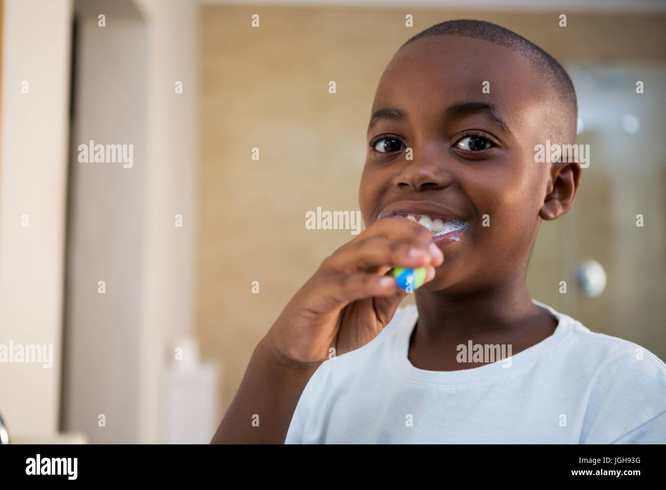 Close-up portrait of smiling boy with toothbrush at domestic bathroom ...
