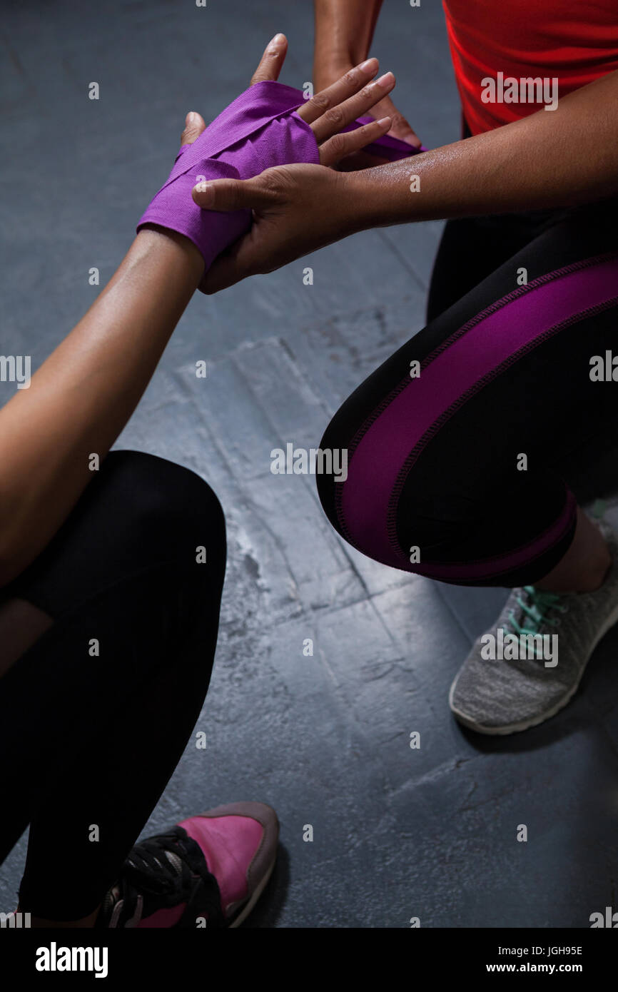 Trainer tying hand wrap on woman hand in fitness studio Stock Photo - Alamy