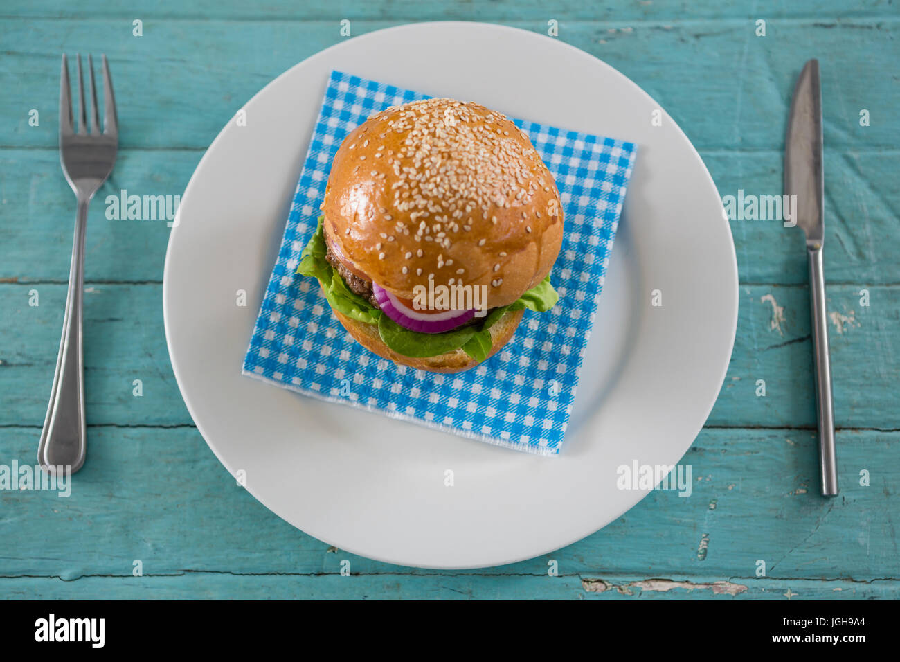 Overhead view of burger on napkin in plate at wooden table Stock Photo ...