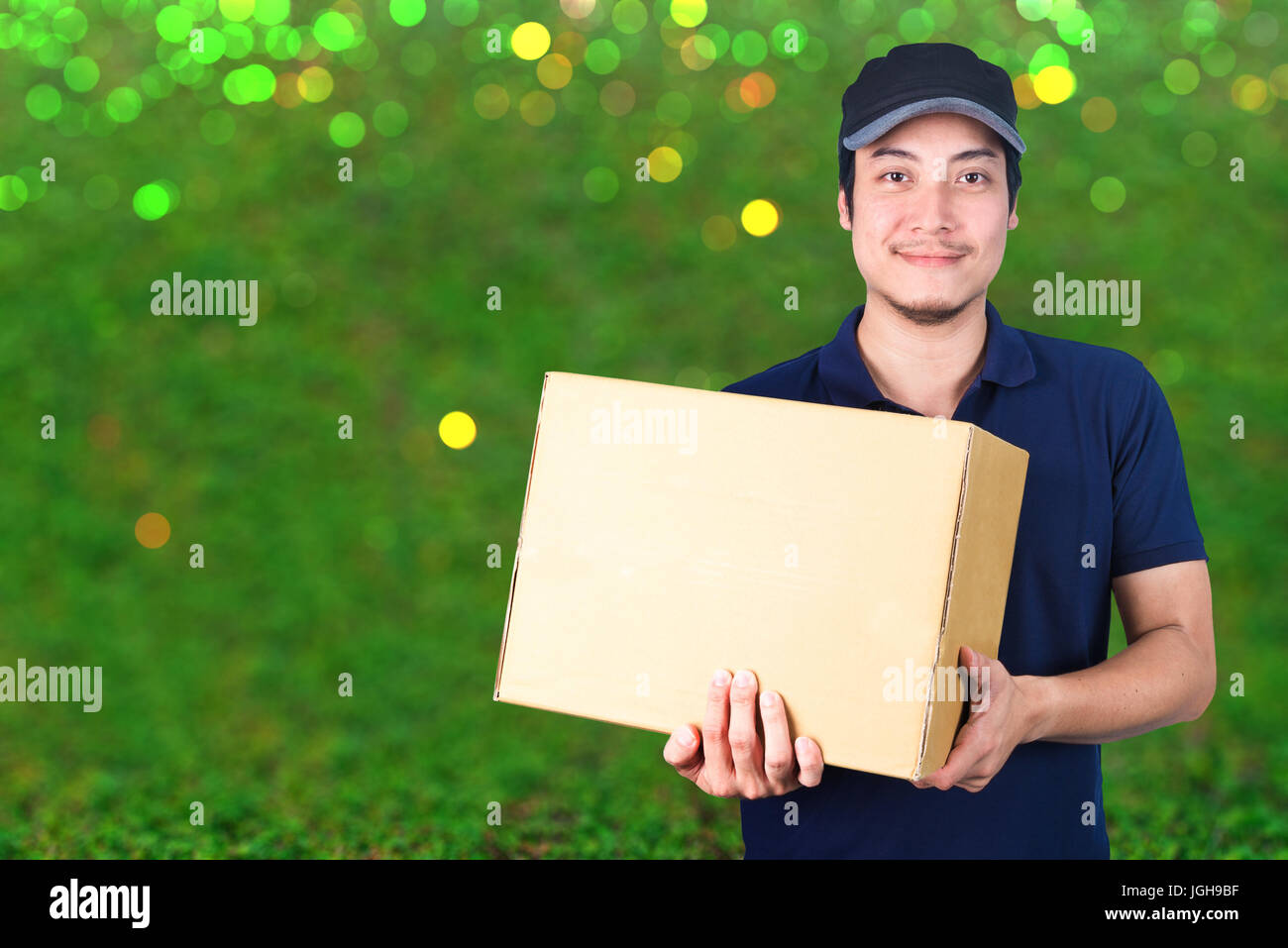 Asian smile Delivery man with cardboard box in hand standing on blurred ...