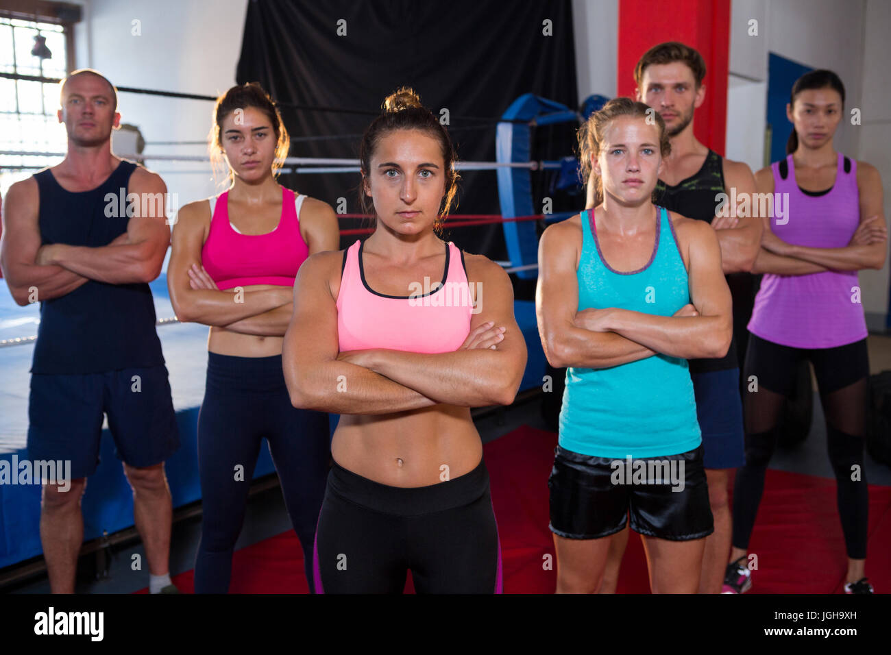 Portrait of confident young athletes standing with arms crossed against ...