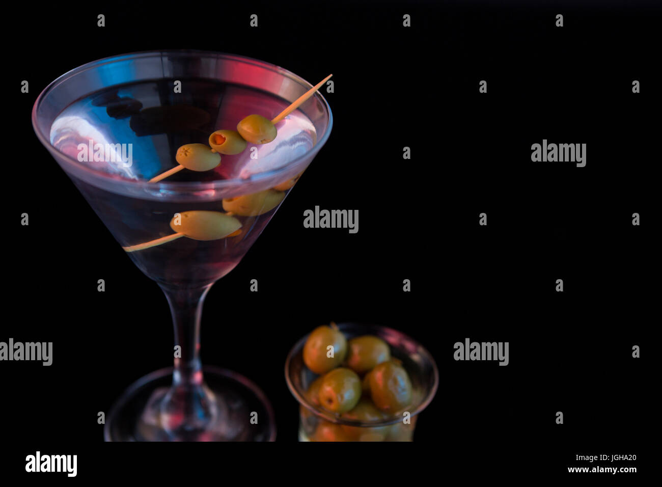 Close-up of cocktail martini with olives on table against black ...