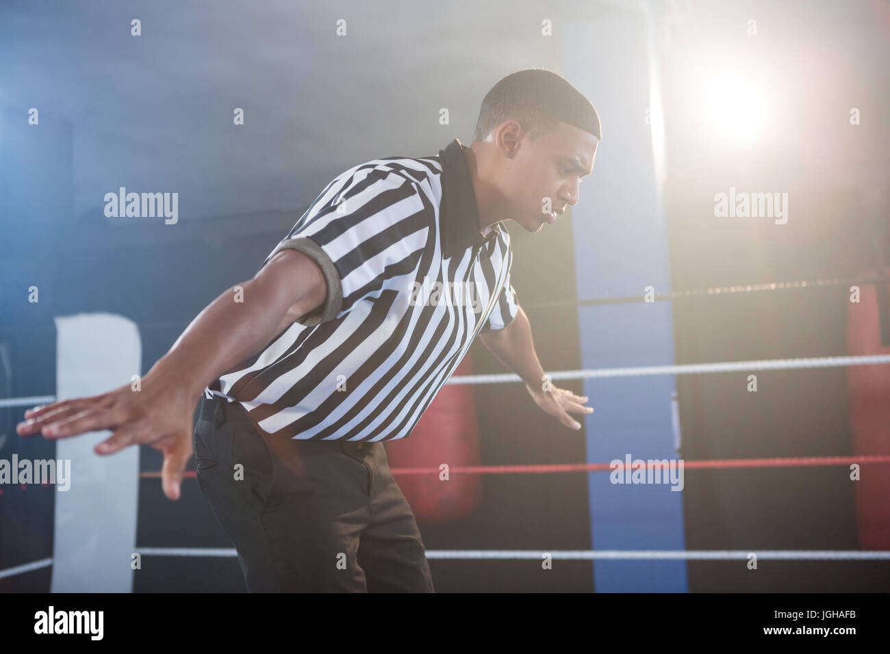 Young male referee showing hand sign in boxing ring at fitness studio ...