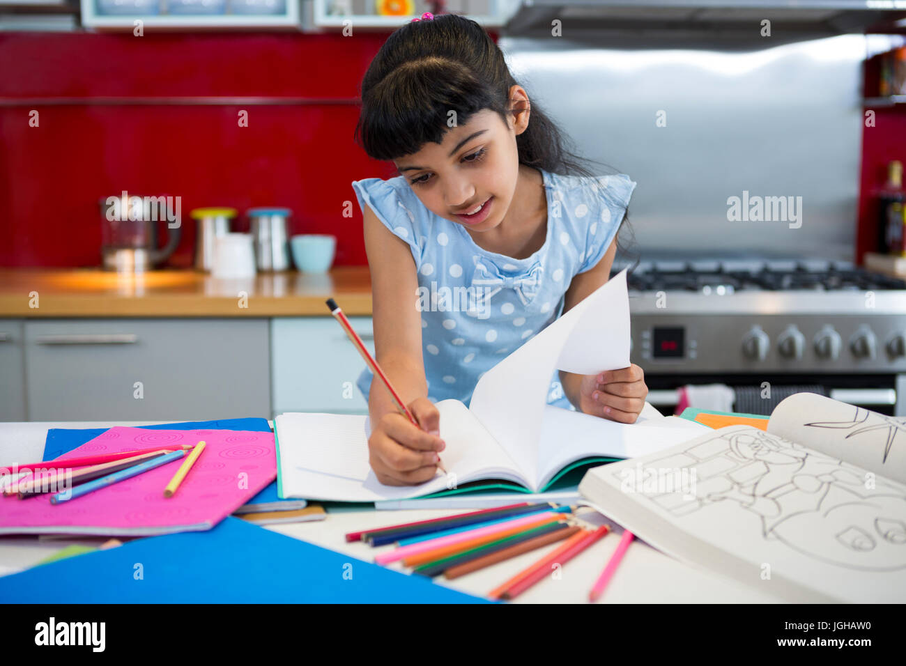 Girl drawing in book at kitchen counter Stock Photo - Alamy