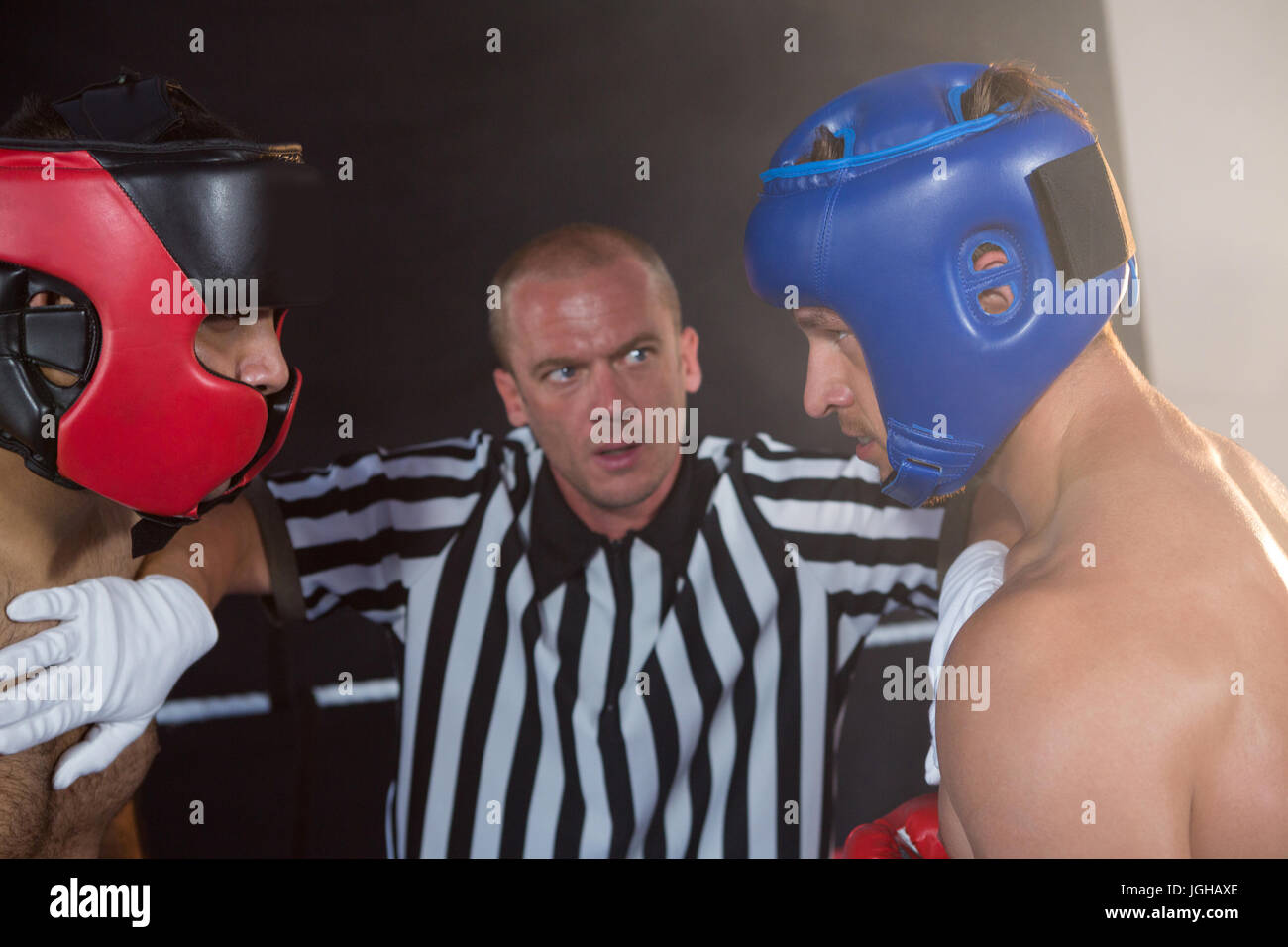 Referee stopping aggressive male boxers in boxing ring Stock Photo - Alamy