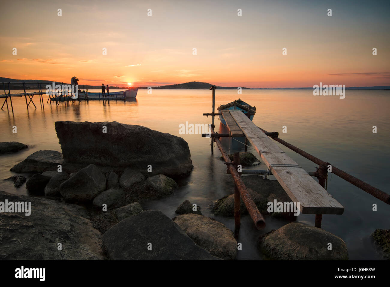 Old Pier, boat and rocks sunset Stock Photo - Alamy