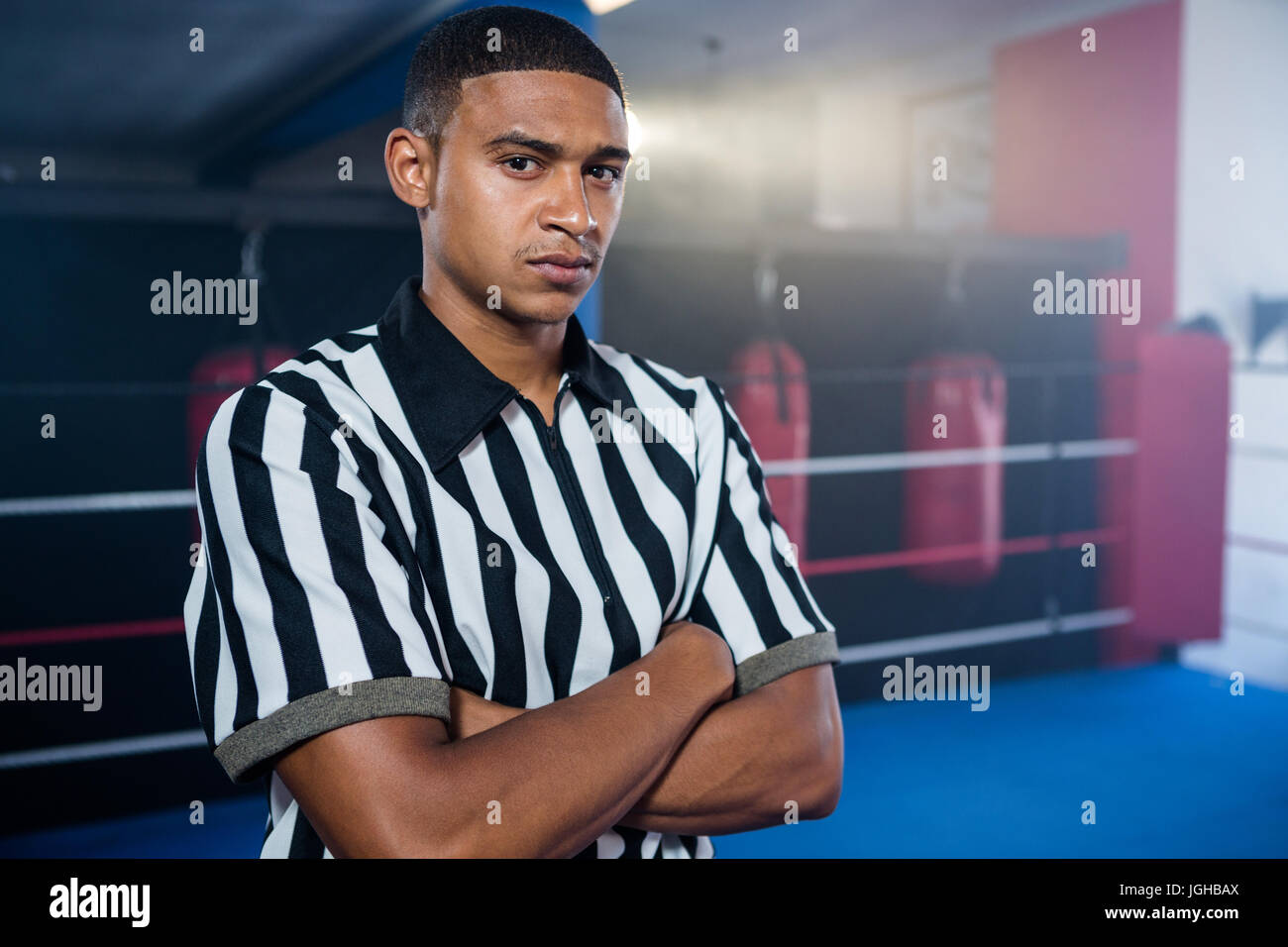 Portrait of confident male referee with arms crossed against boxing ...