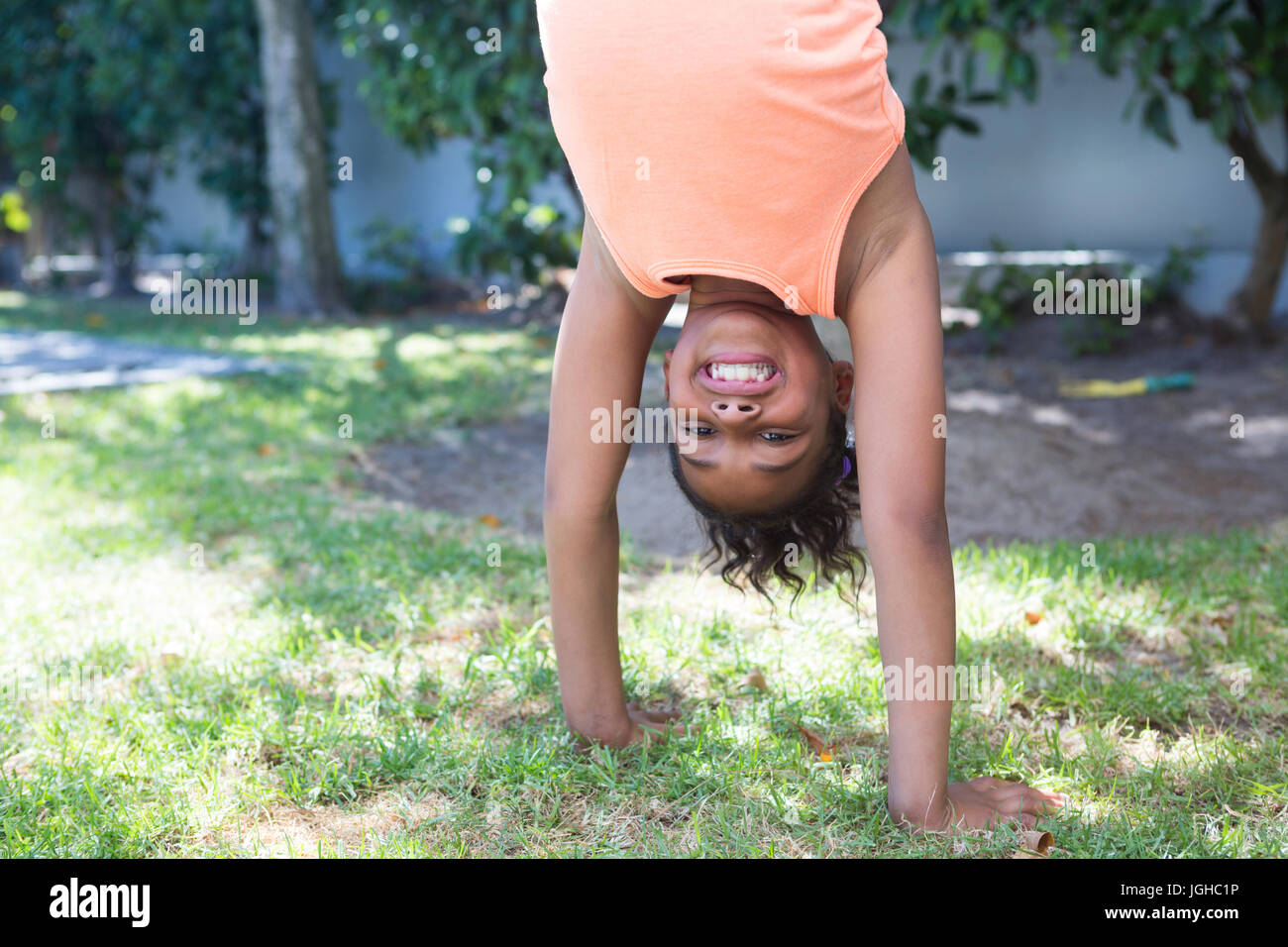 Portrait of girl practicing handstand in yard Stock Photo - Alamy