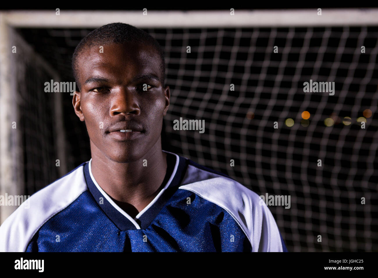 Portrait of young male soccer player standing against goal post Stock ...
