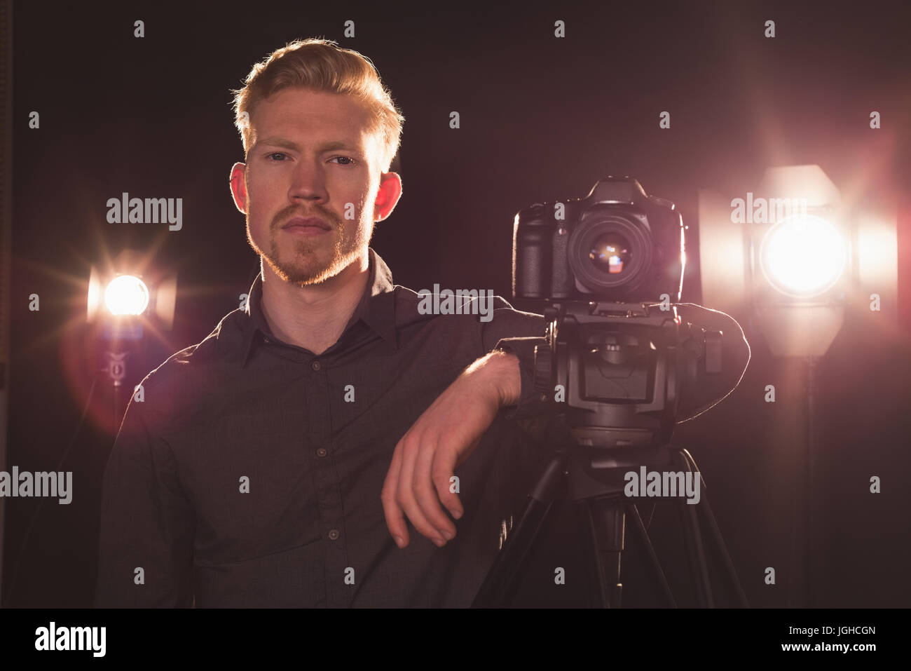 Portrait of photographer standing by camera at illuminated studio Stock ...