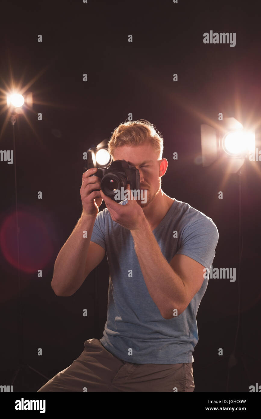 Male photographer photographing from camera at illuminated studio Stock ...