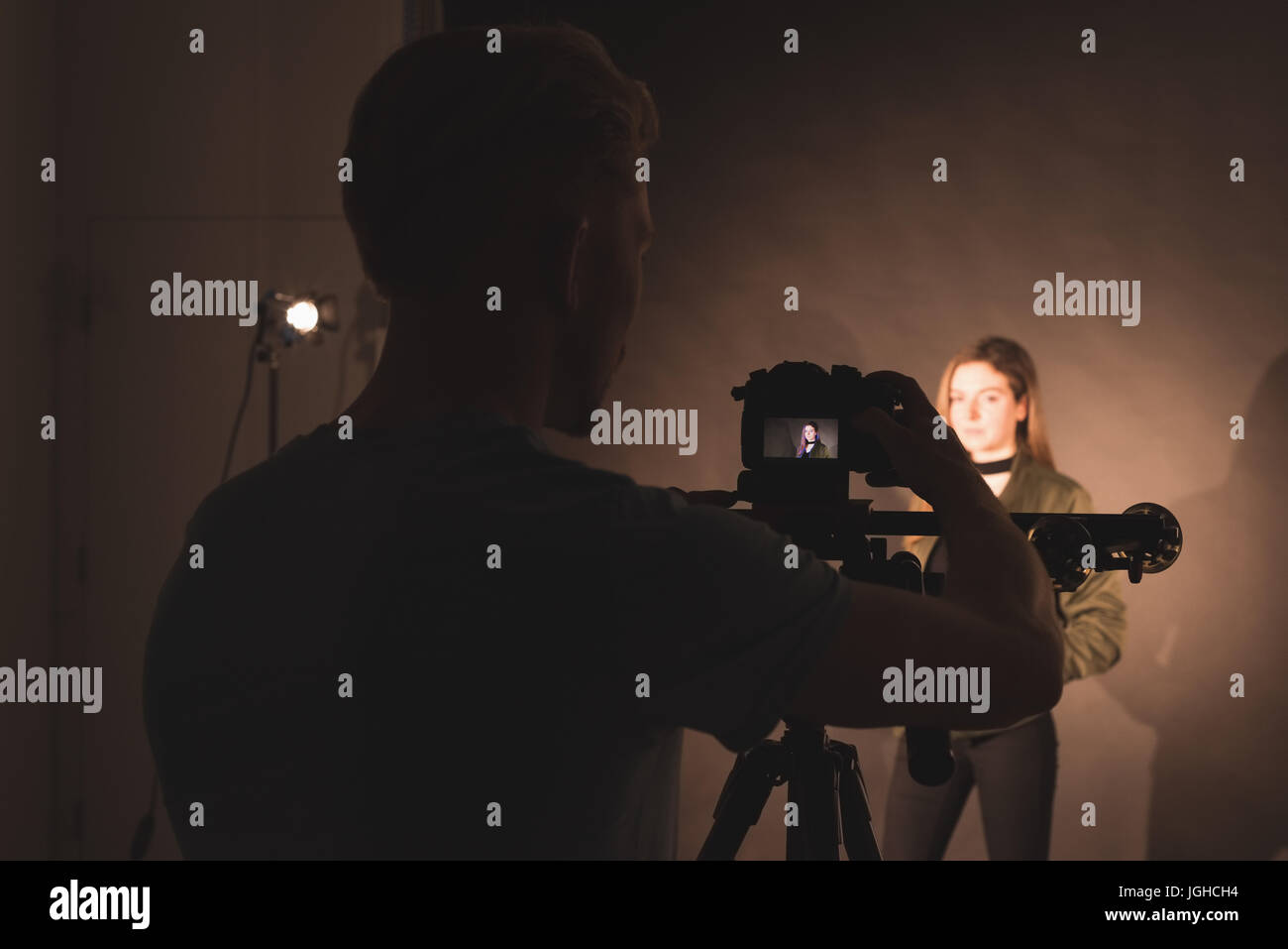 Photographer photographing female model standing at studio Stock Photo ...
