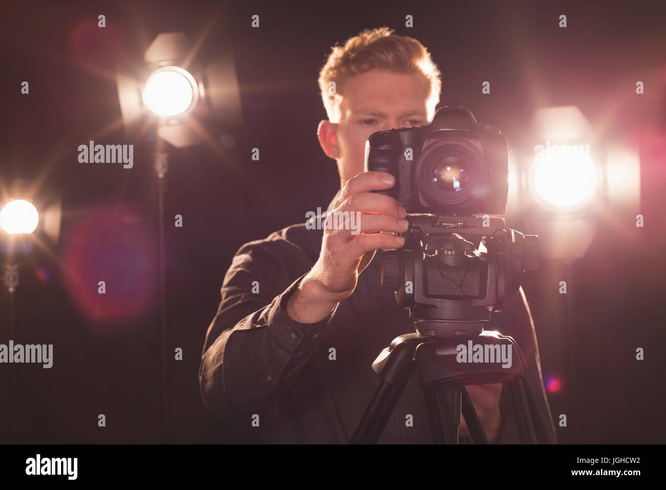 Male photographer adjusting camera at illuminated studio Stock Photo ...