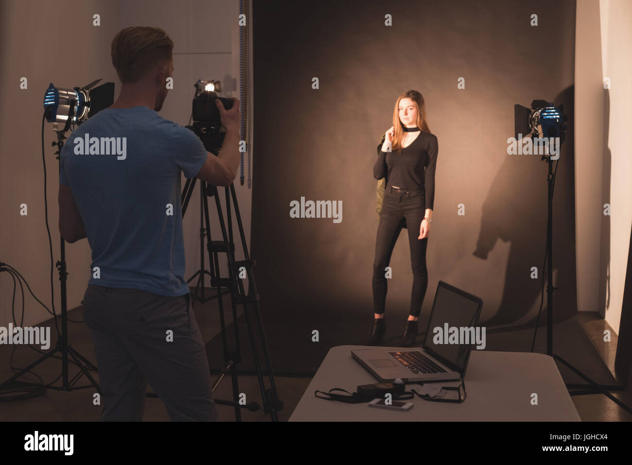 Rear view of man photographing female model standing at studio Stock ...