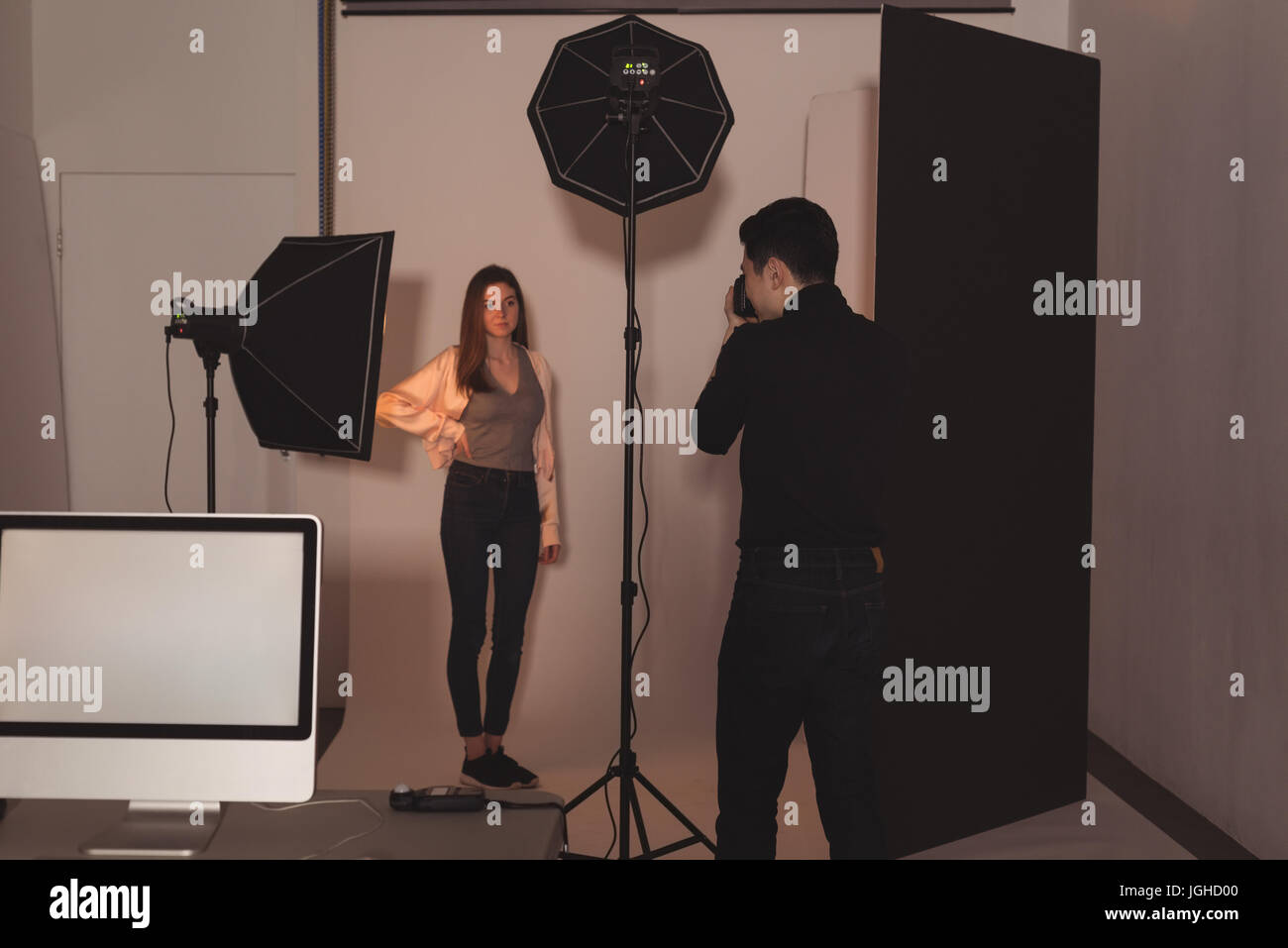 Photographer photographing female model standing at film studio Stock ...