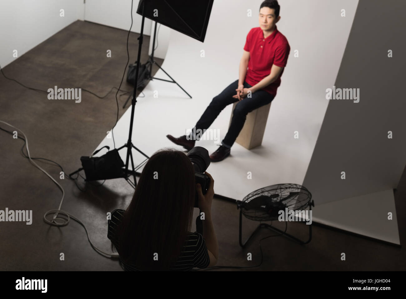 Female photographer photographing young man posing at studio Stock ...