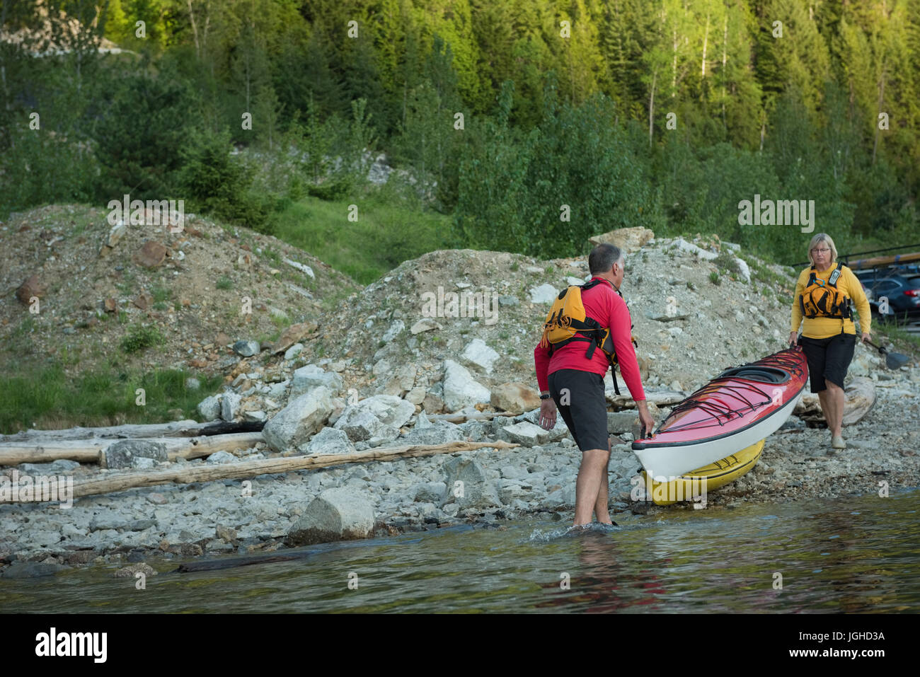 Couple carrying kayak in lake at forest Stock Photo - Alamy