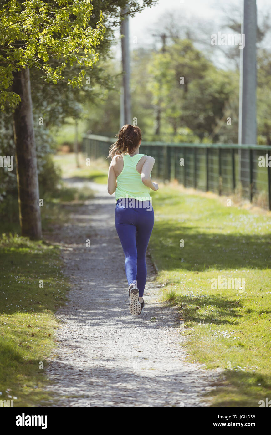 Rear view full length of female athlete running on pathway Stock Photo ...