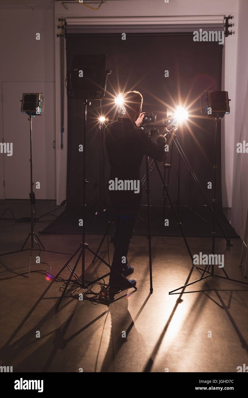 Rear view full length of photographer adjusting camera at illuminated ...