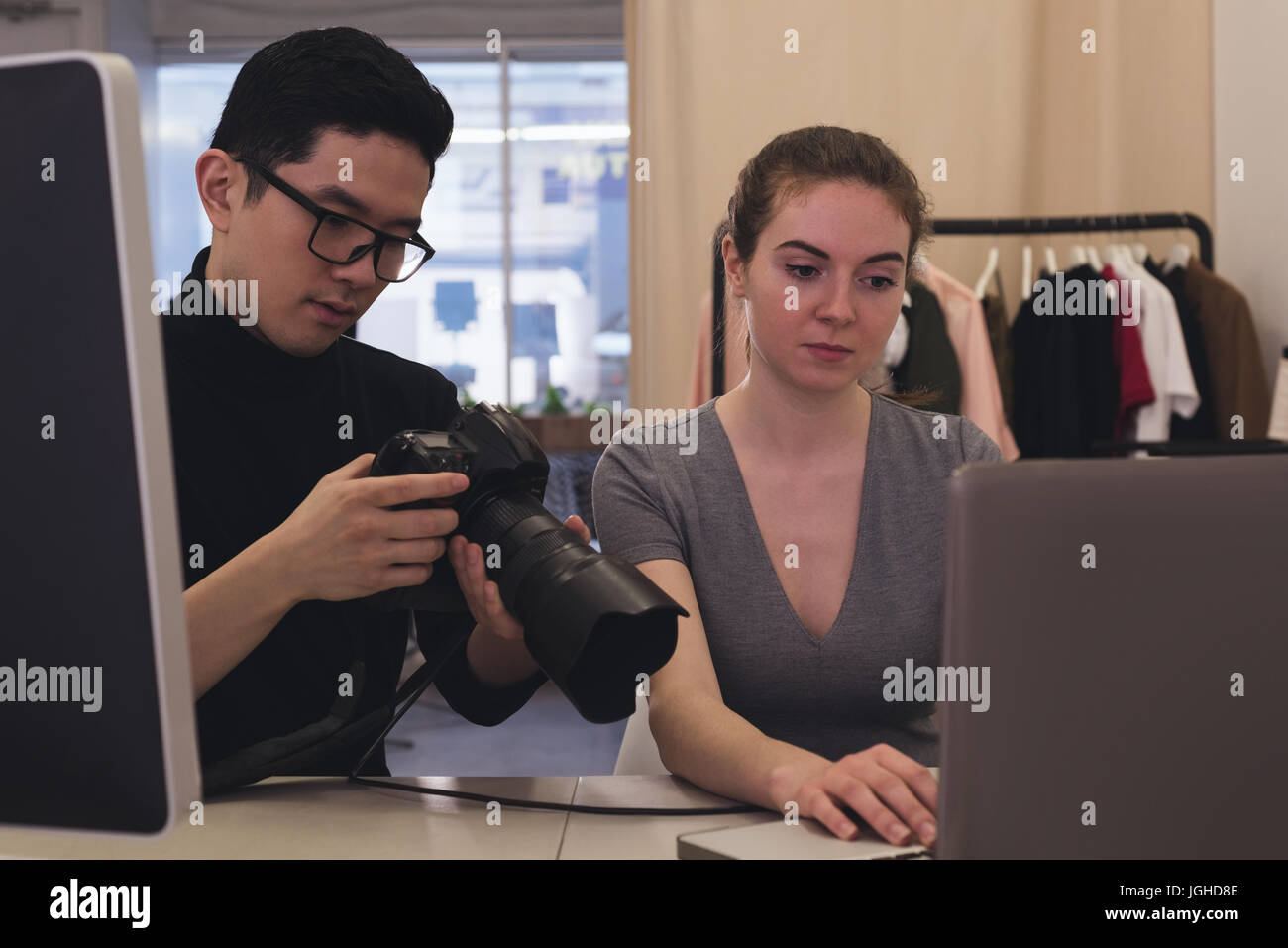 Female assistant with photographer using laptop at studio Stock Photo ...