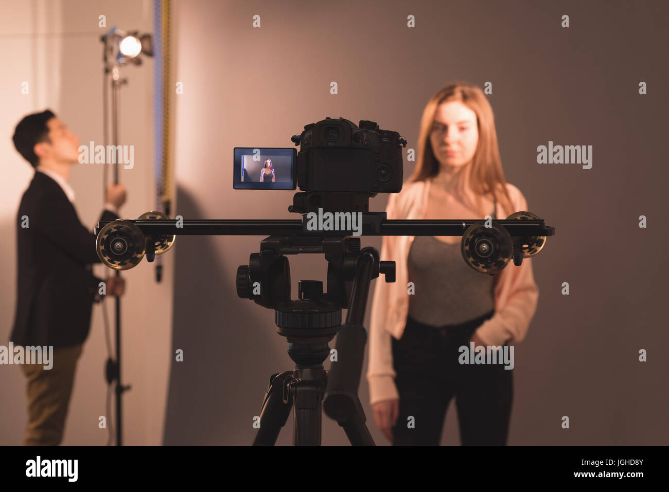 Video camera photographing female model with photographer adjusting ...