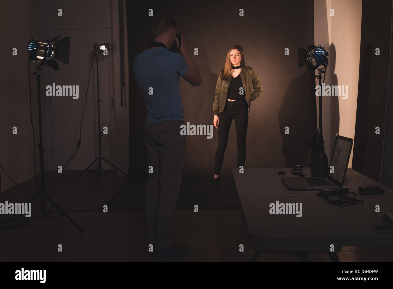 Rear view of photographer photographing female model standing at studio ...