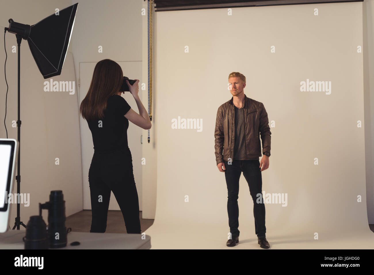 Female photographer photographing man against backdrop at studio Stock ...