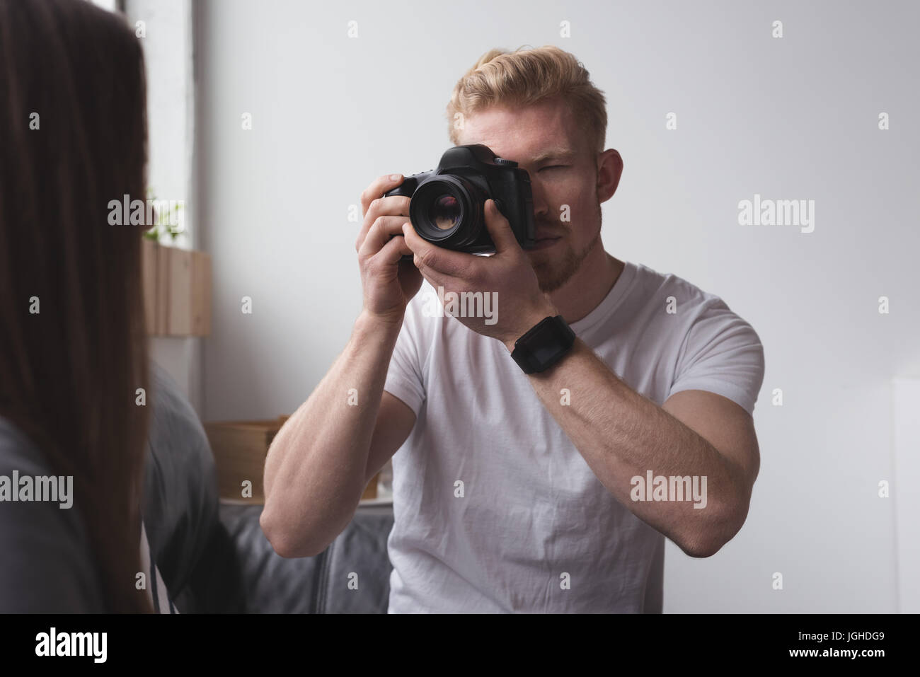 Male photographer photographing model while sitting on sofa at home ...