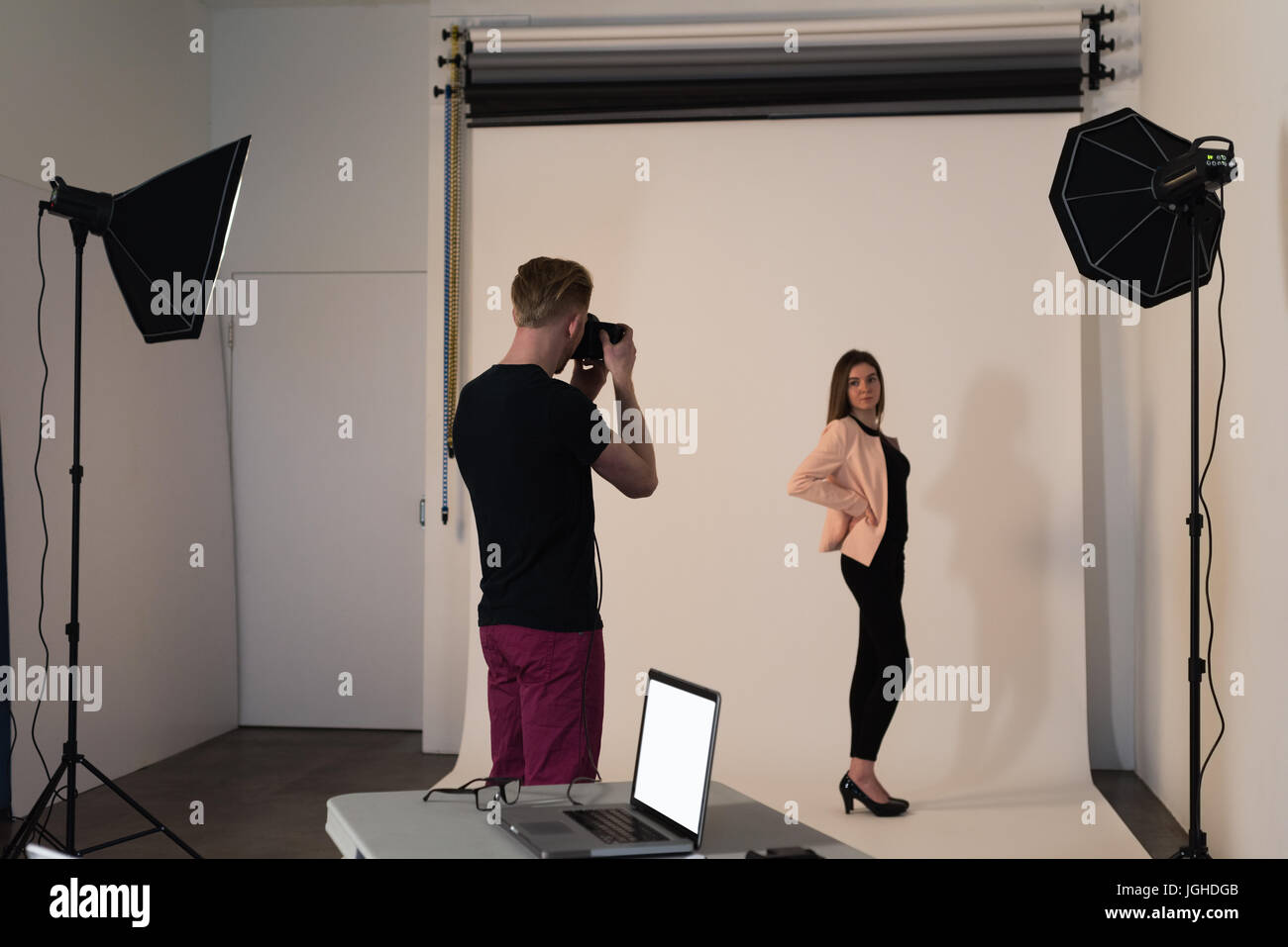 Rear view of man photographing female model at studio Stock Photo - Alamy