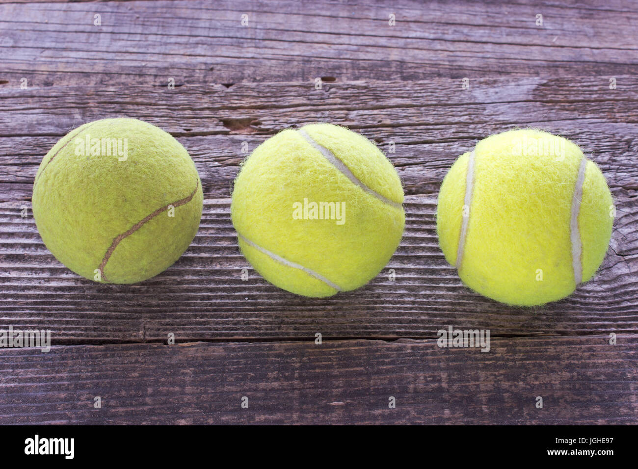 Three used tennis balls on wooden background Stock Photo - Alamy