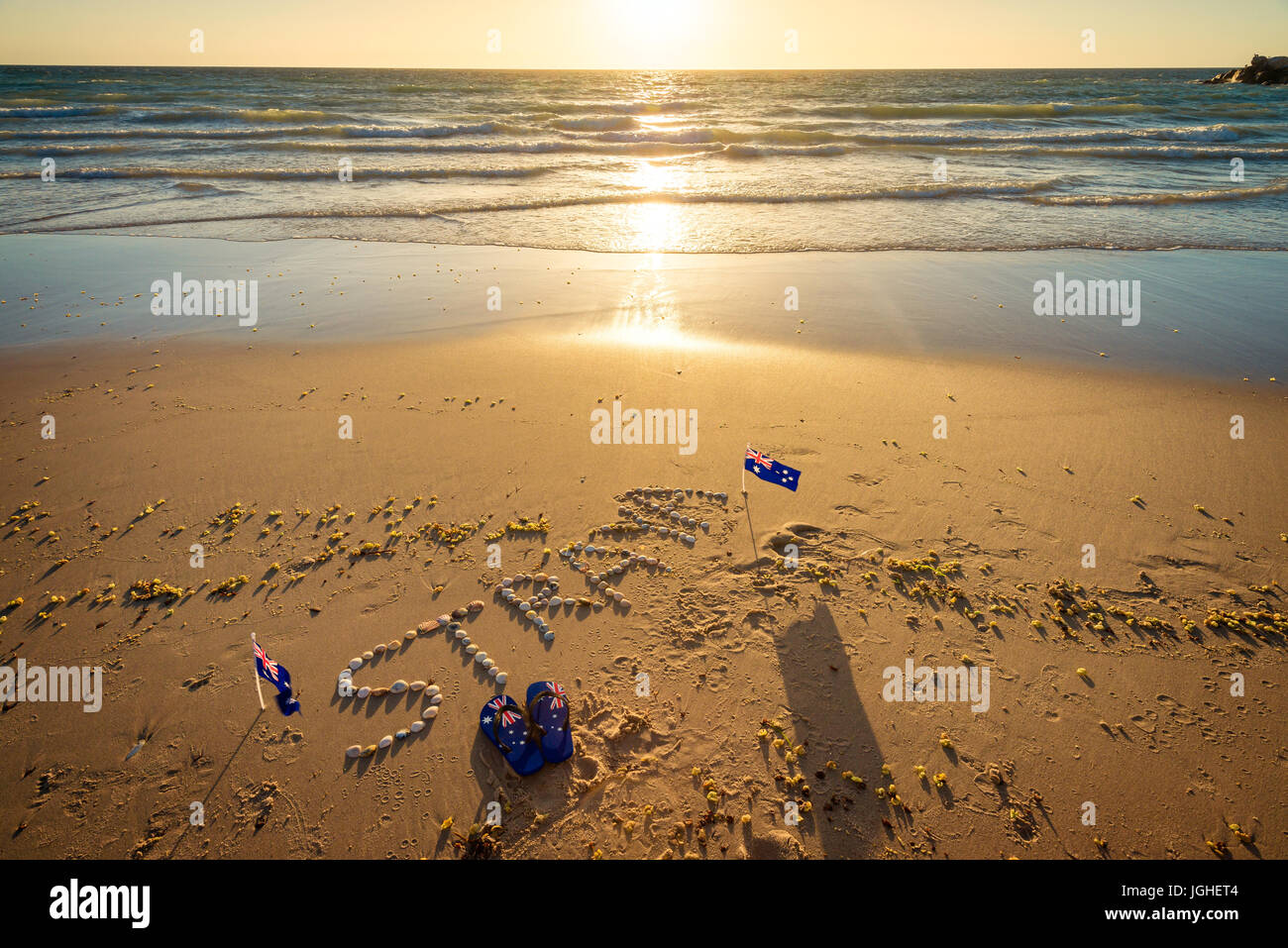 Straya text drawn using shells on sand with flags and thongs. Straya is ...