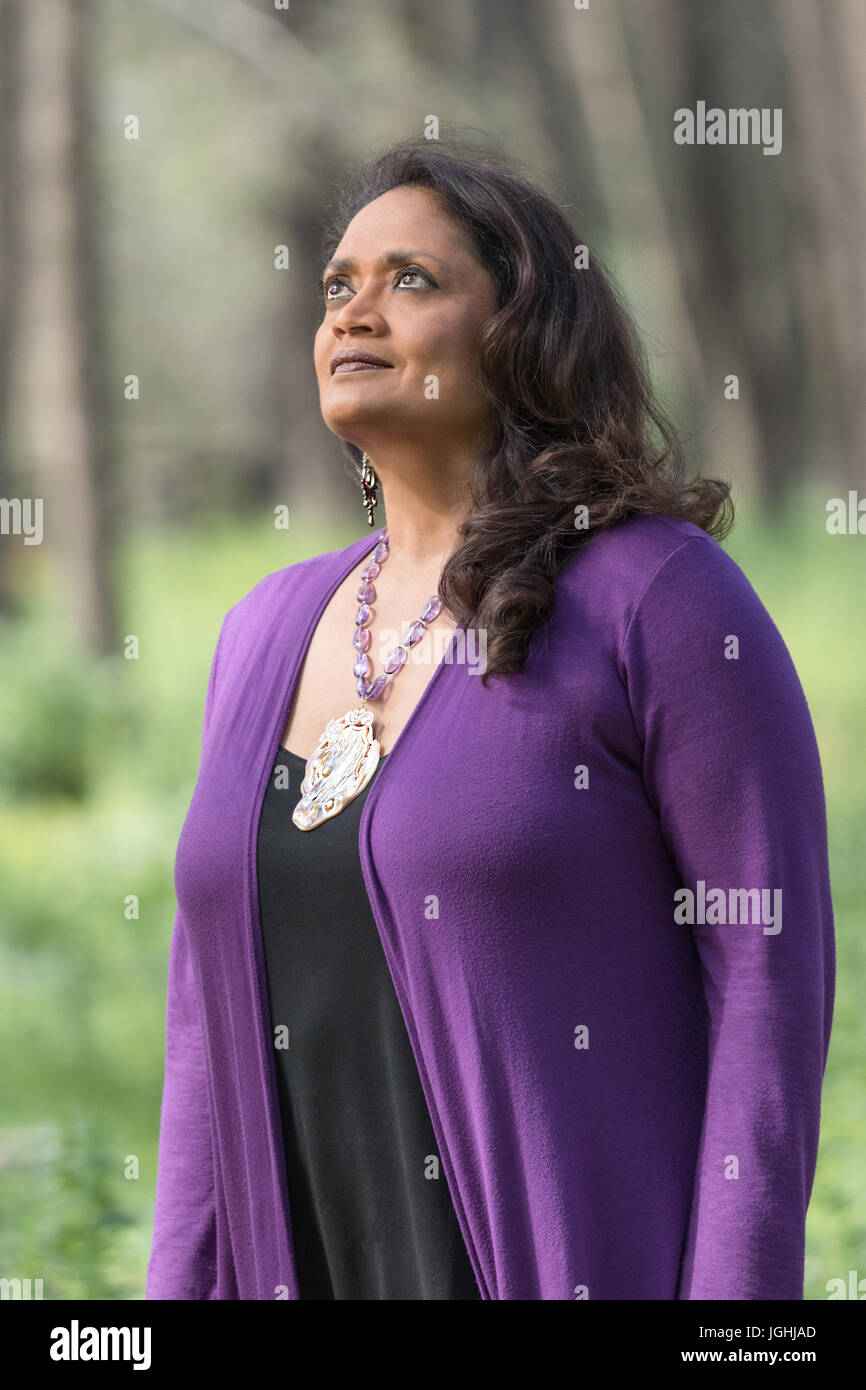 Indian woman in forest looking up to the sky with reverent look on her ...