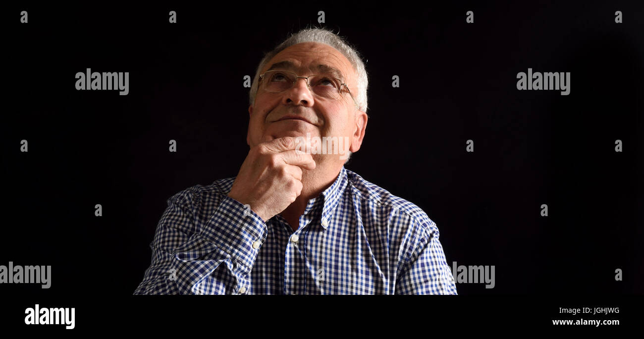 Pensative man on black background Stock Photo - Alamy