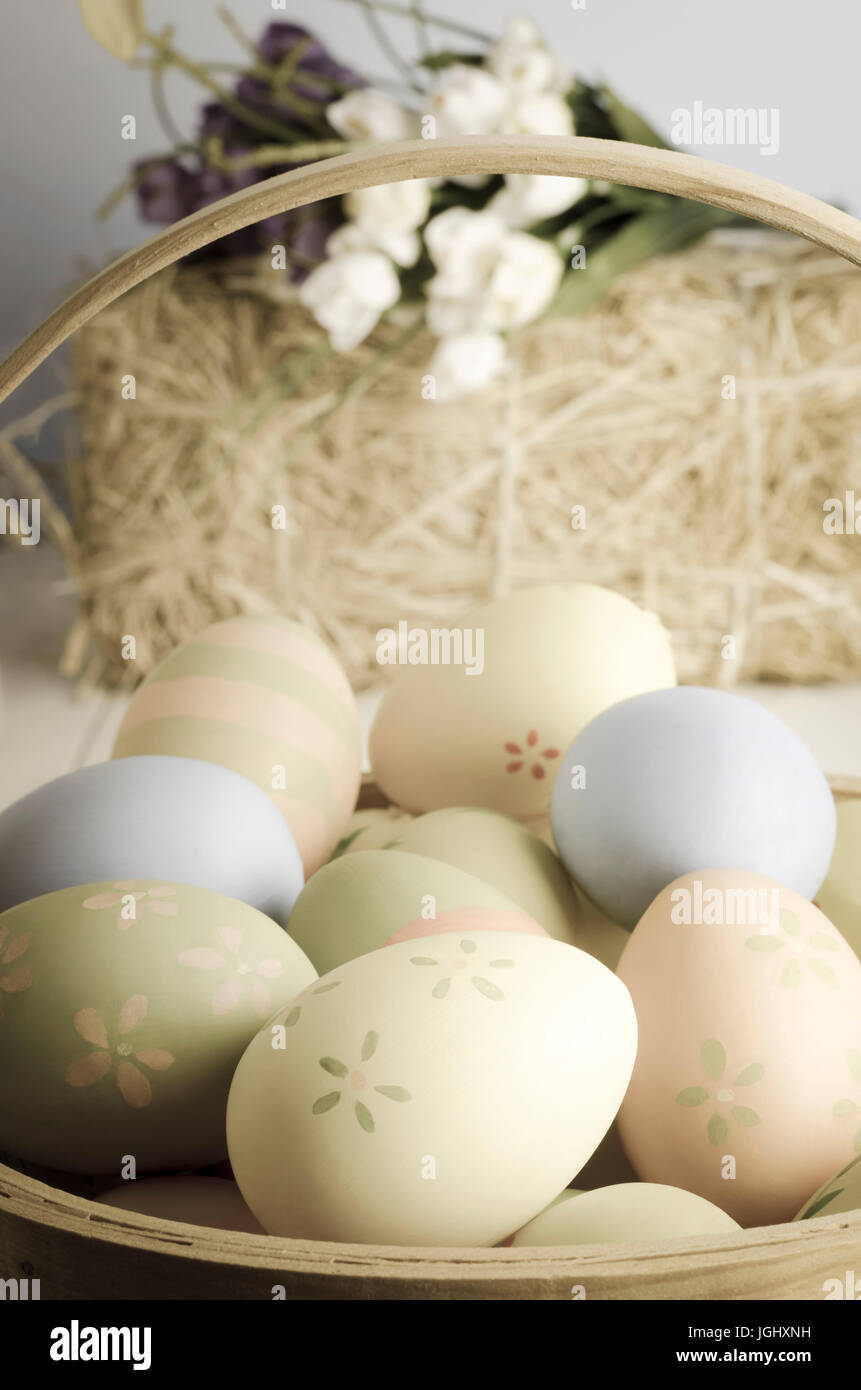 A selection of decorated Easter eggs in a wicker basket on a table ...