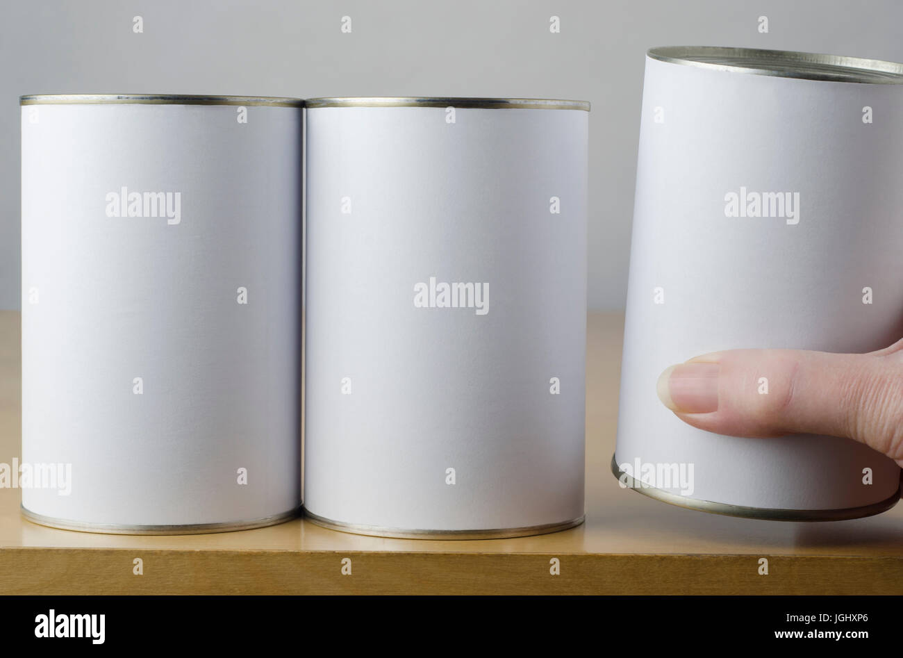 Conceptual image of three tin cans with blank white paper labels on a ...