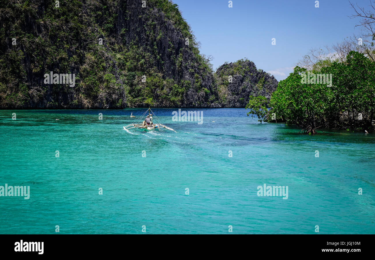 A small traditional boat runs on the sea at sunny day in Palawan ...