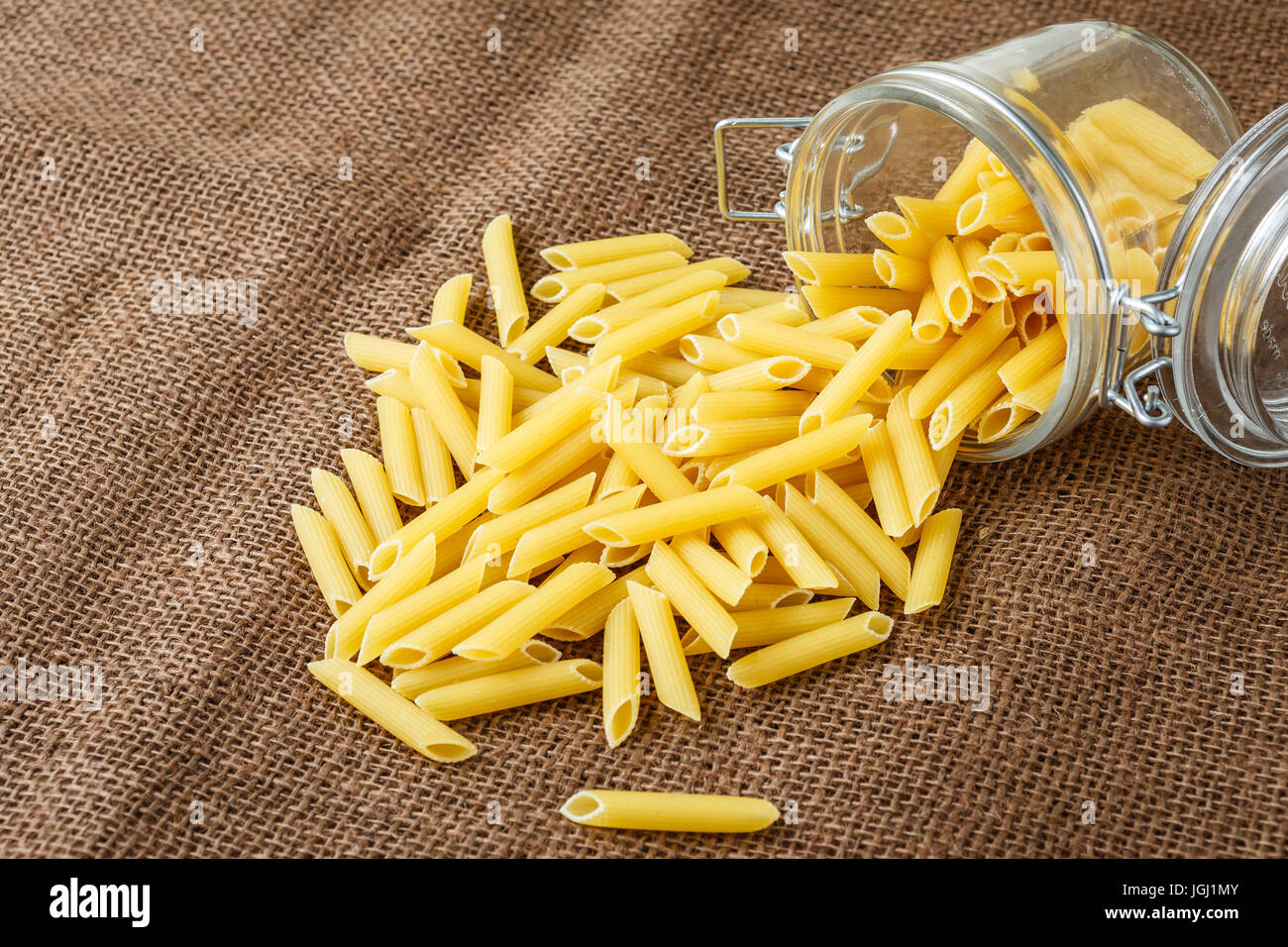 Italian pasta - penne in glass jar on brown background Stock Photo - Alamy