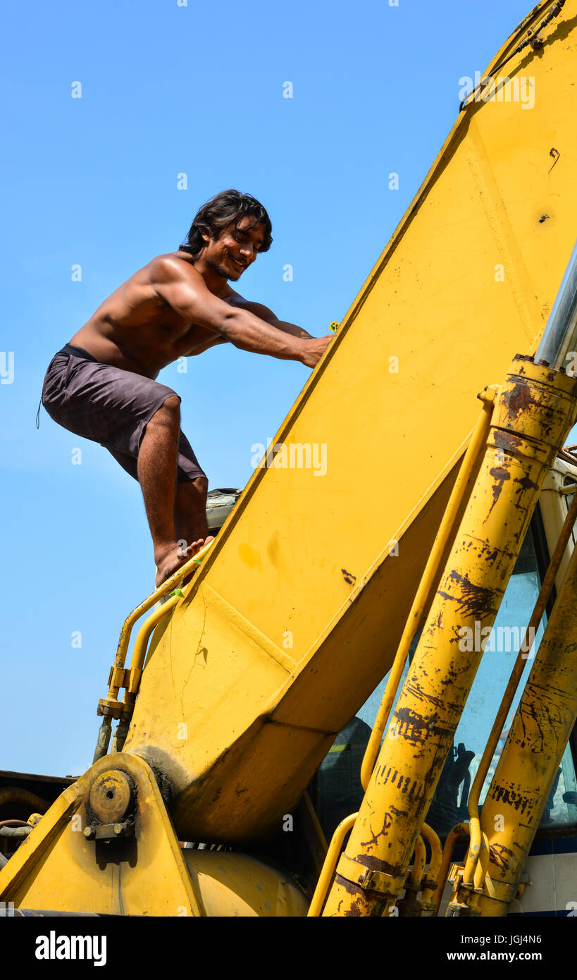An Indian young man climbing on the construction machine Stock Photo ...