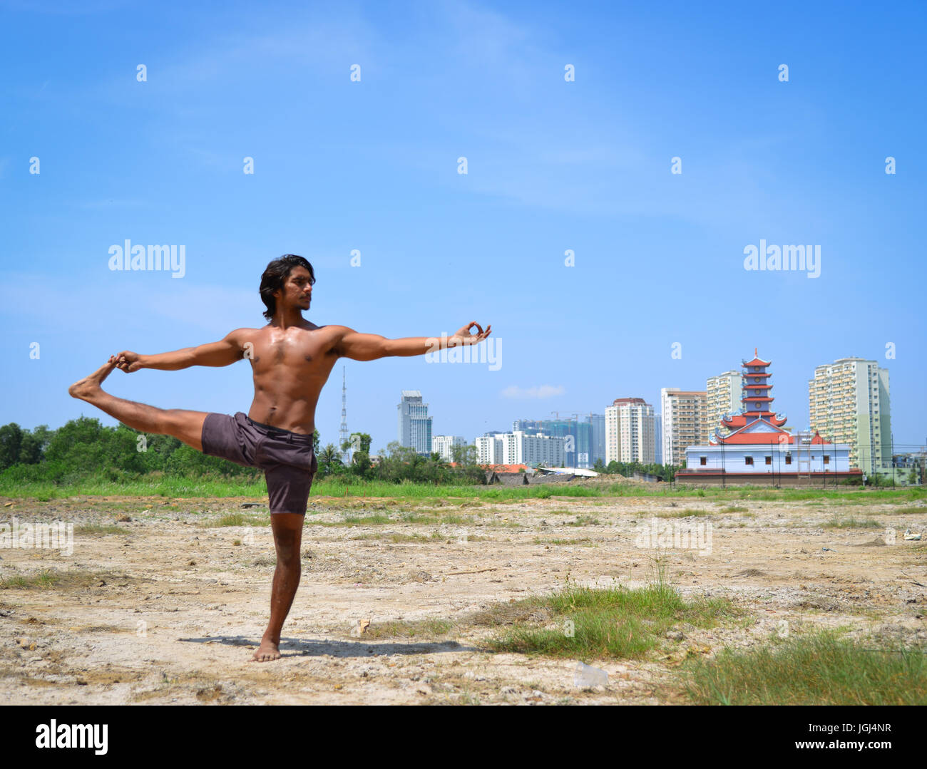 An Indian young man doing Yoga poses at sunny day, with cityscape ...