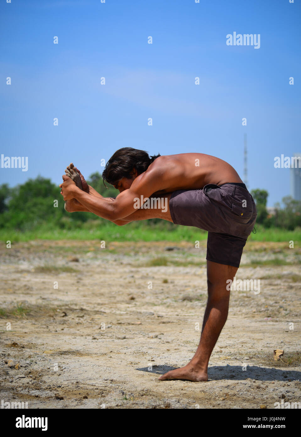 An Indian muscle man doing Yoga poses at sunny day, with cityscape ...