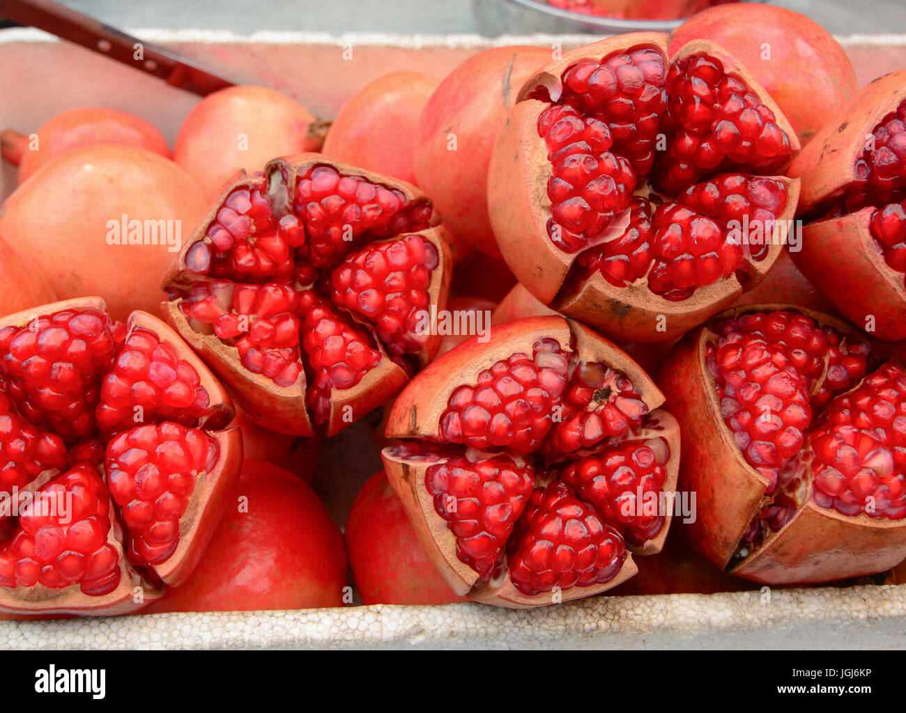 Top view of ripe pomegranate fruits split open to reveal clusters of ...